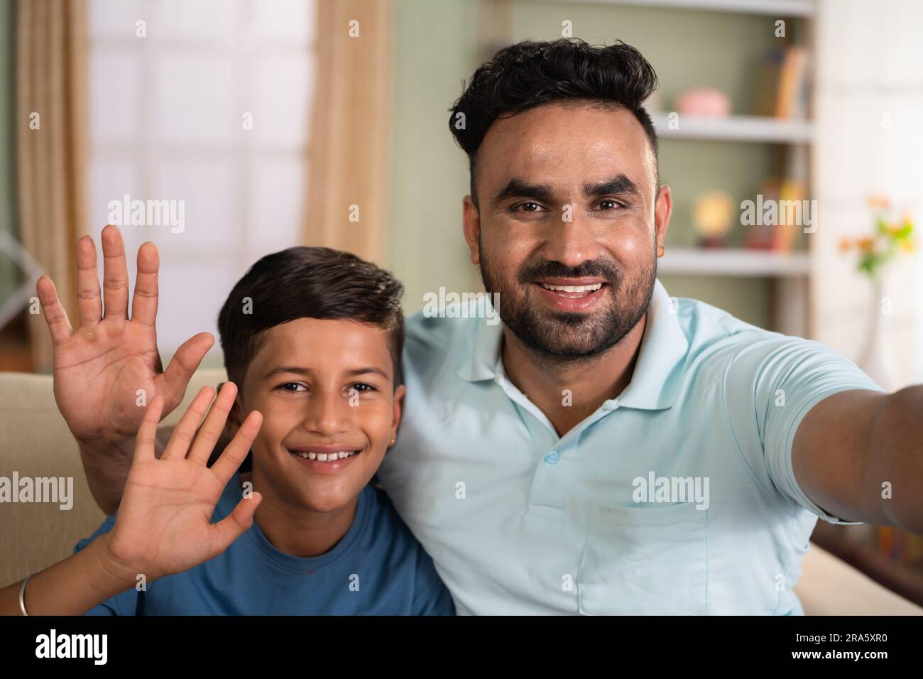 Happy smiling indian father with son talking video call by holding ...