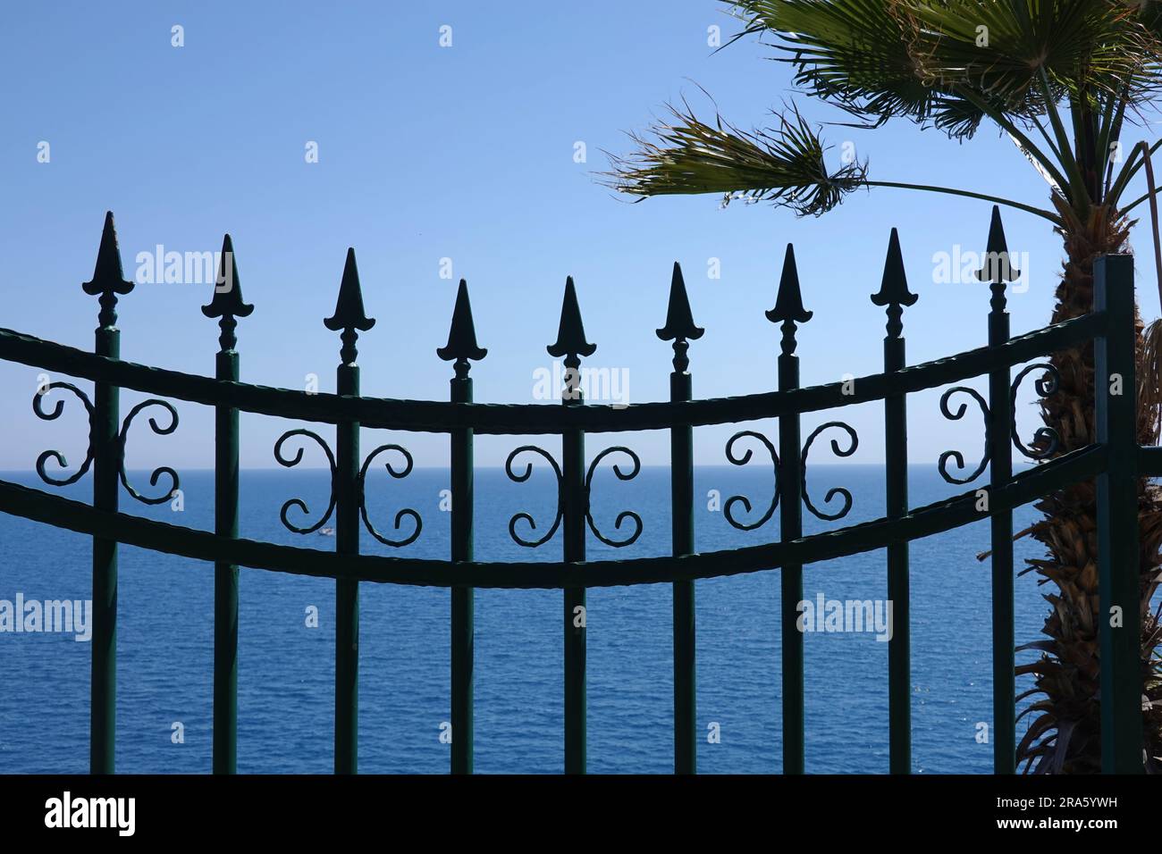 View through black sharp fencing to azure sea water surface till ...