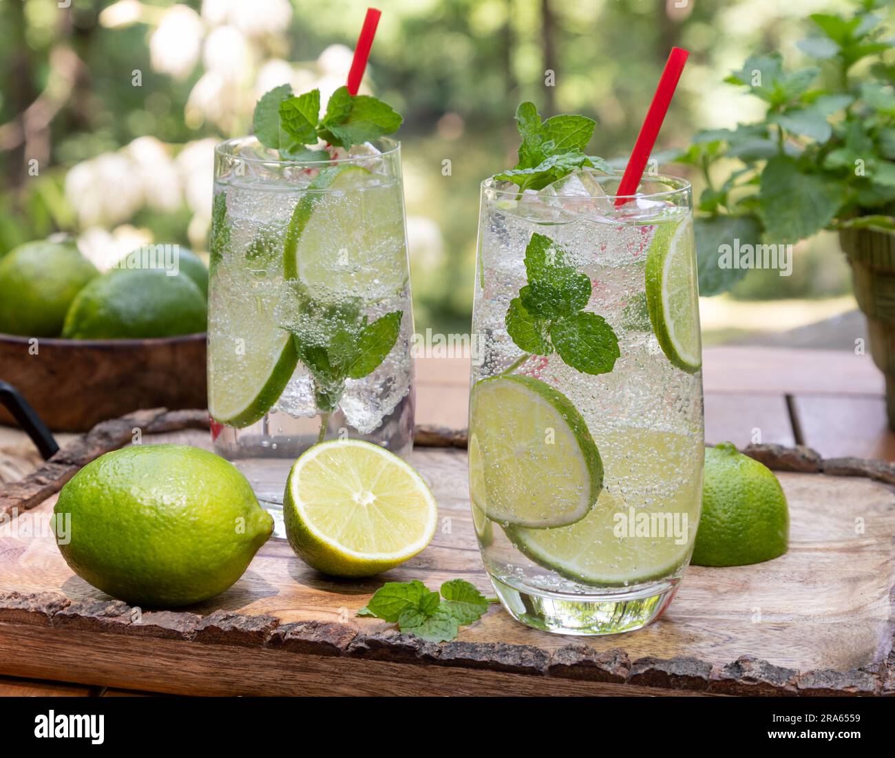 Mojito cocktail with lime slices and mint leaves outdoors on wooden ...