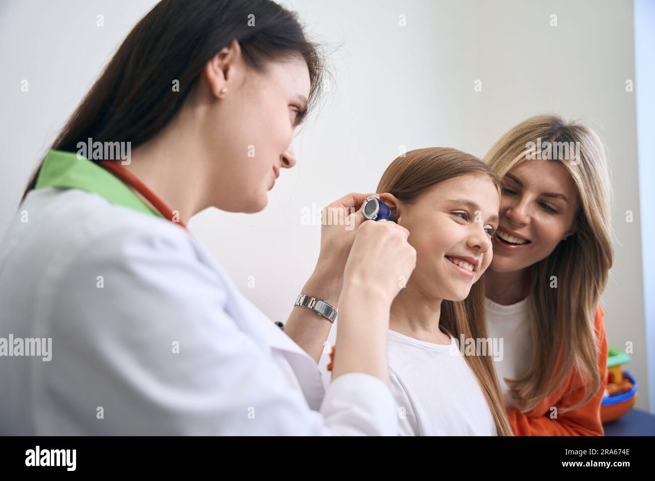 ENT specialist using otoscope with light to check ear to girl patient ...