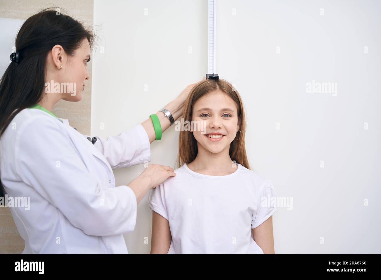Woman nurse checking little girl height using special measuring plank ...