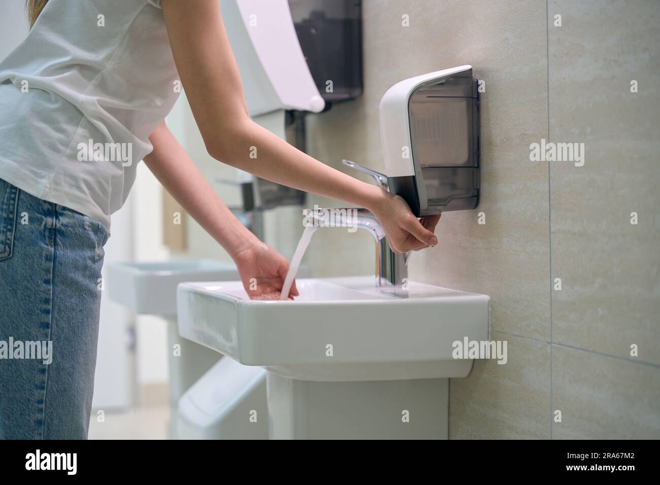 Little girl taking soap using soap dispenser to carefully wash her ...
