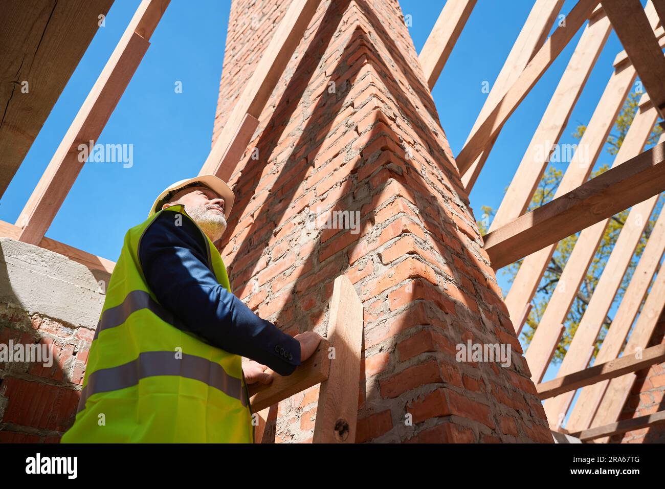 Building engineer standing on ladder looking at roof beams Stock Photo ...