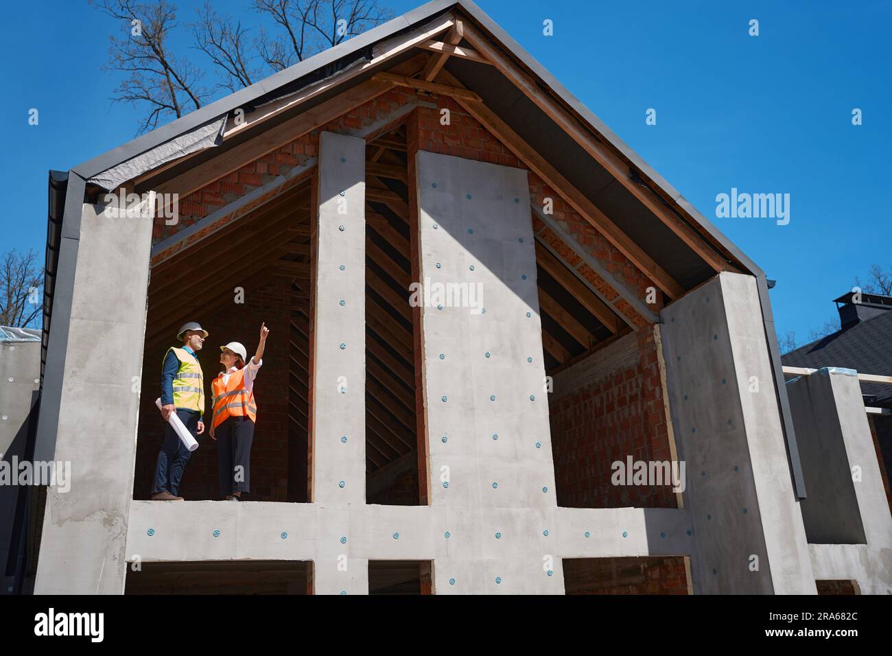 Project manager and foreman standing on high floor of almost builded house Stock Photo - Alamy