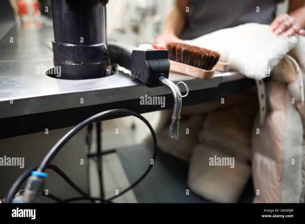 Dry-cleaning operator cleaning fur with special brush and steam gun ...