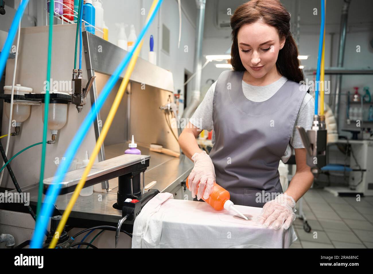 Dry-cleaning operator adding solvent to spots, treating clothes before ...