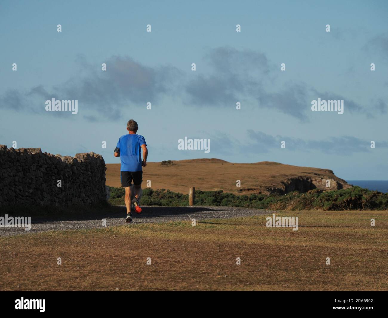 Man Jogging on coastal path, Rhossili bay, Gower Peninsula, Wales Stock ...