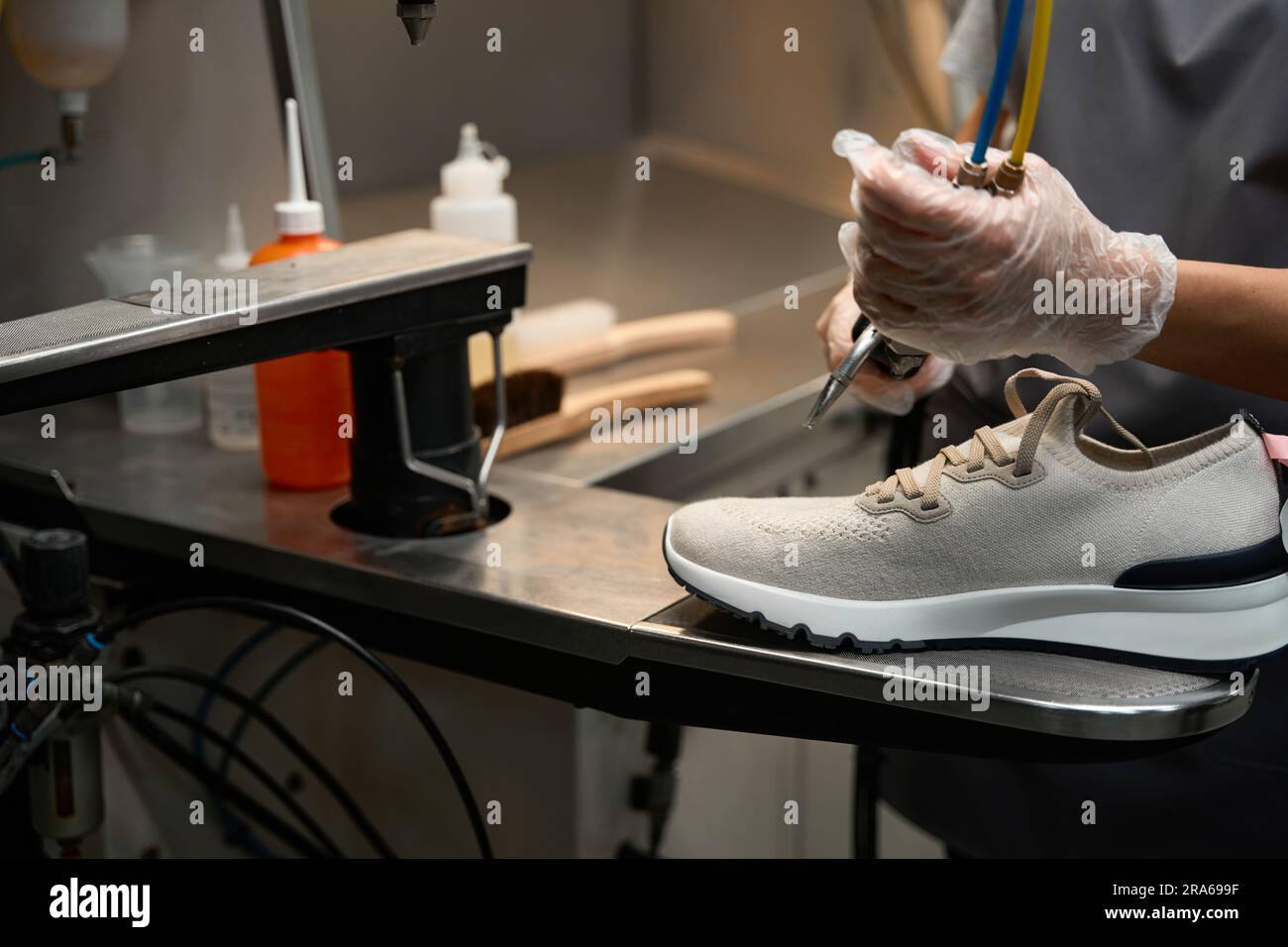 Dry-cleaning service operator cleaning sneakers with special steam gun ...