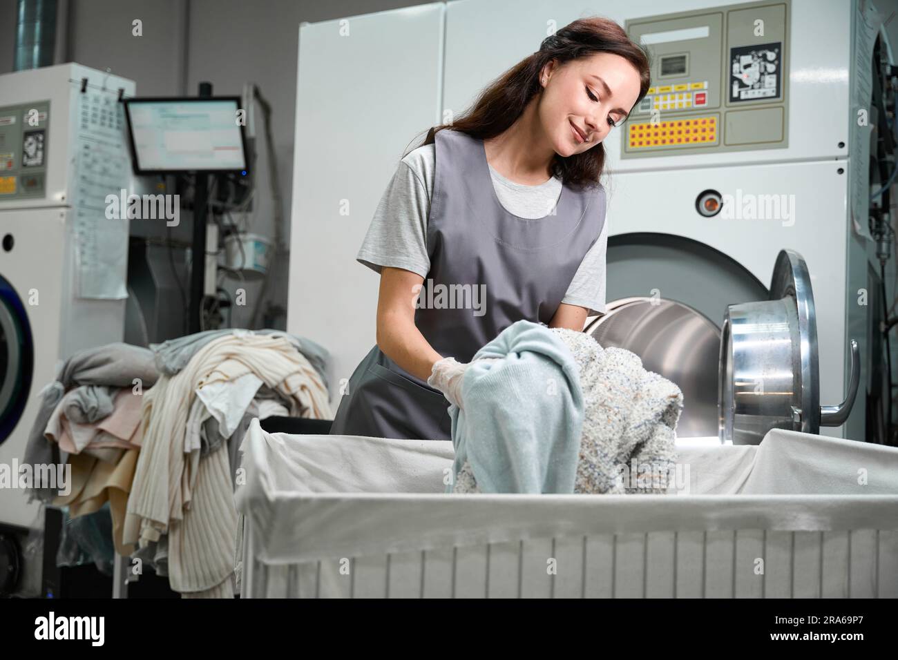 Lady dry service worker removing washed clothes from big machine Stock ...