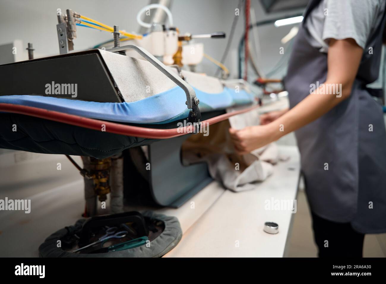 Laundry office worker using steam press table to dry and iron clothes ...