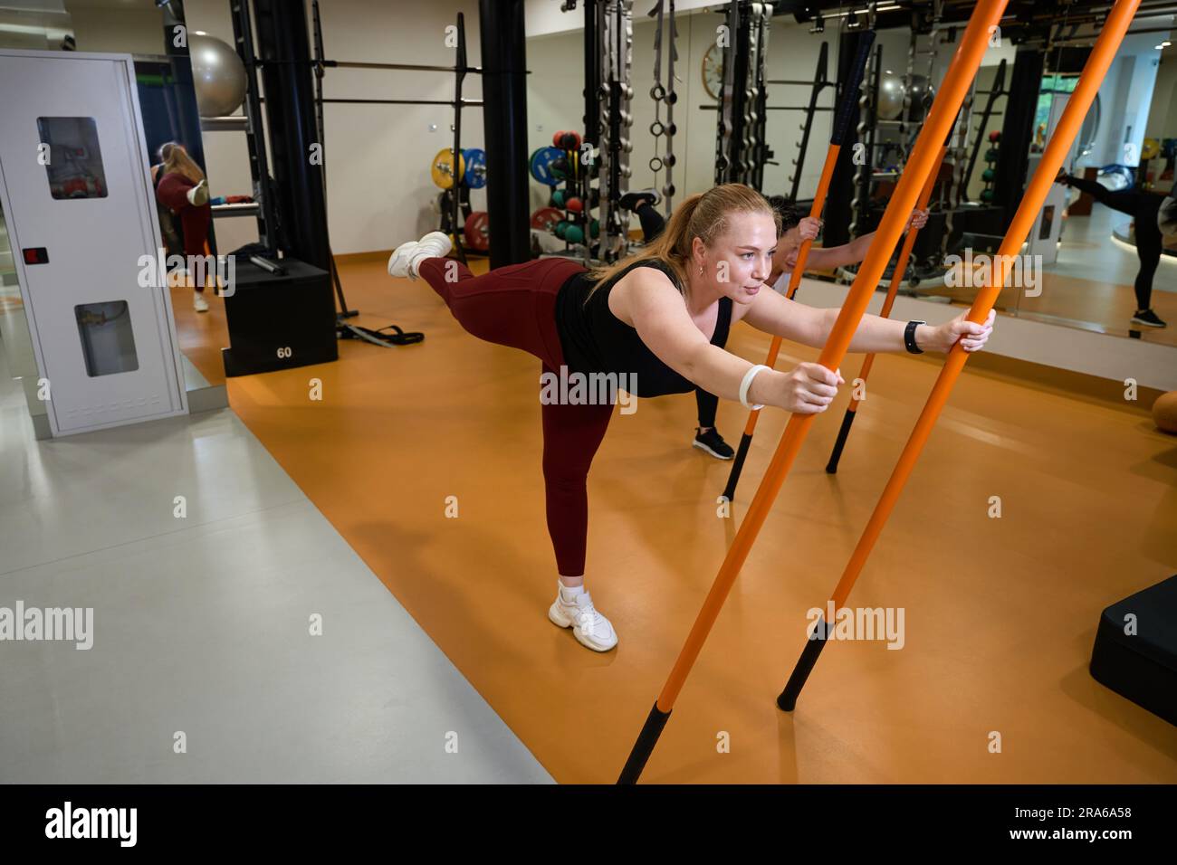 Women in fitness clinic perform balance exercises with gymnastic sticks ...