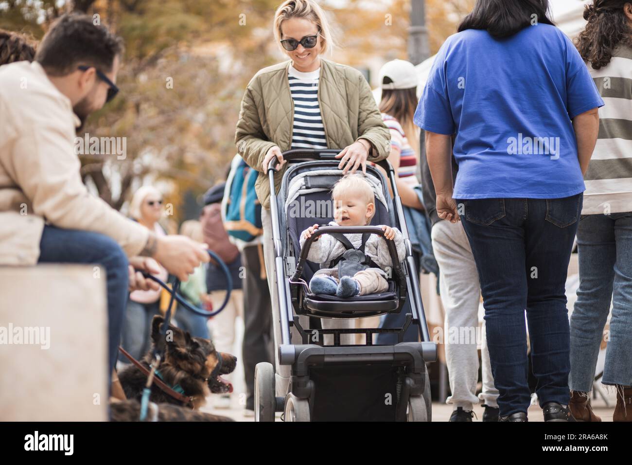 Mother walking and pushing his infant baby boy child in stroller in ...