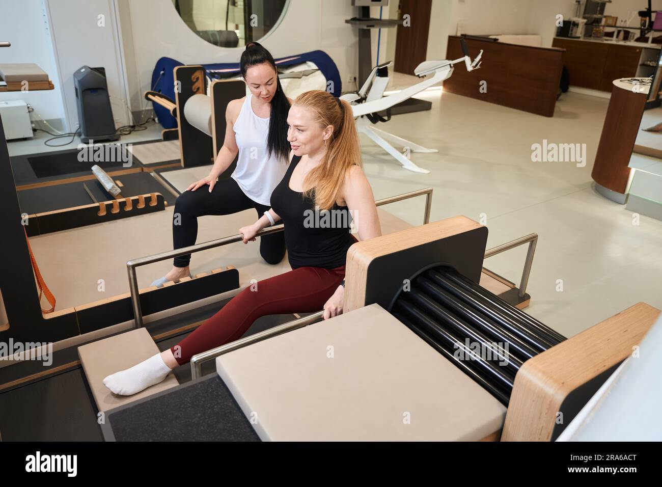 Fitness clinic trainer helps lady perform muscle stretching exercises ...