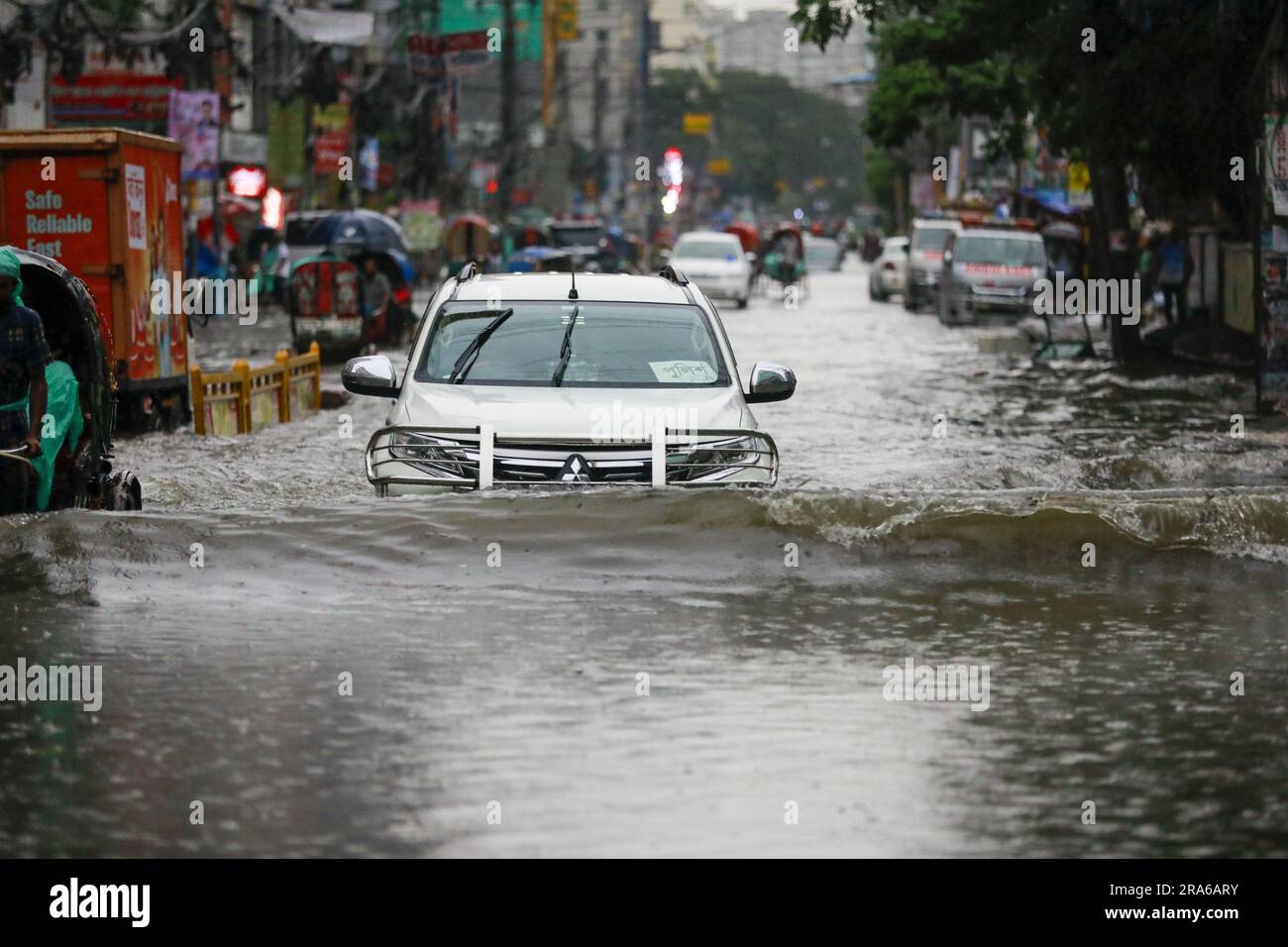Dhaka, Bangladesh. 1st July, 2023. Vehicles make their way through a waterlogged street after ...