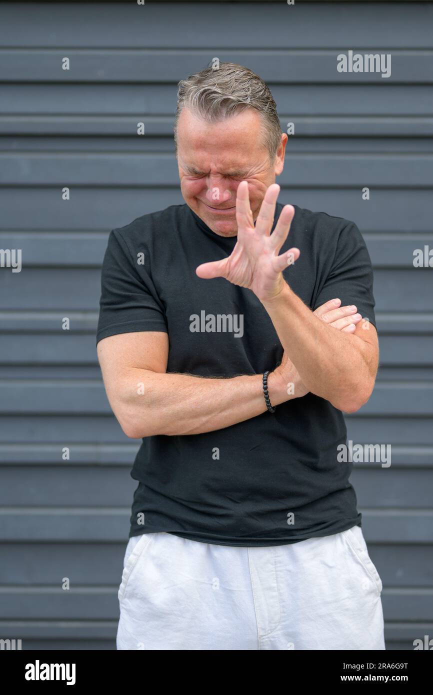 Three quarter length portrait of a distressed elderly man with one hand ...