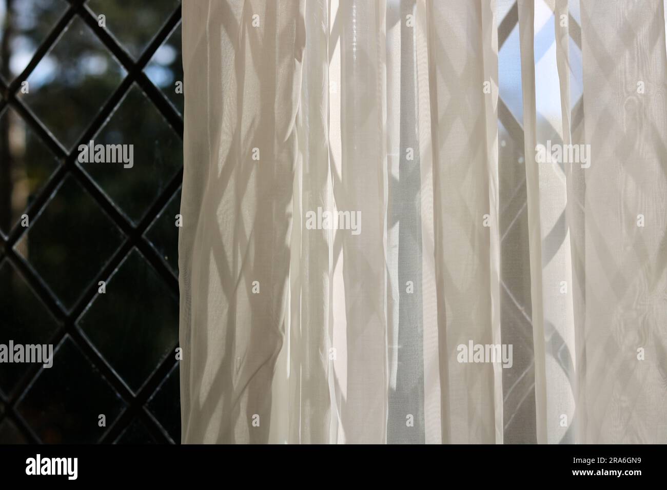 Voile curtain in front of geometric leaded light glass window Stock ...