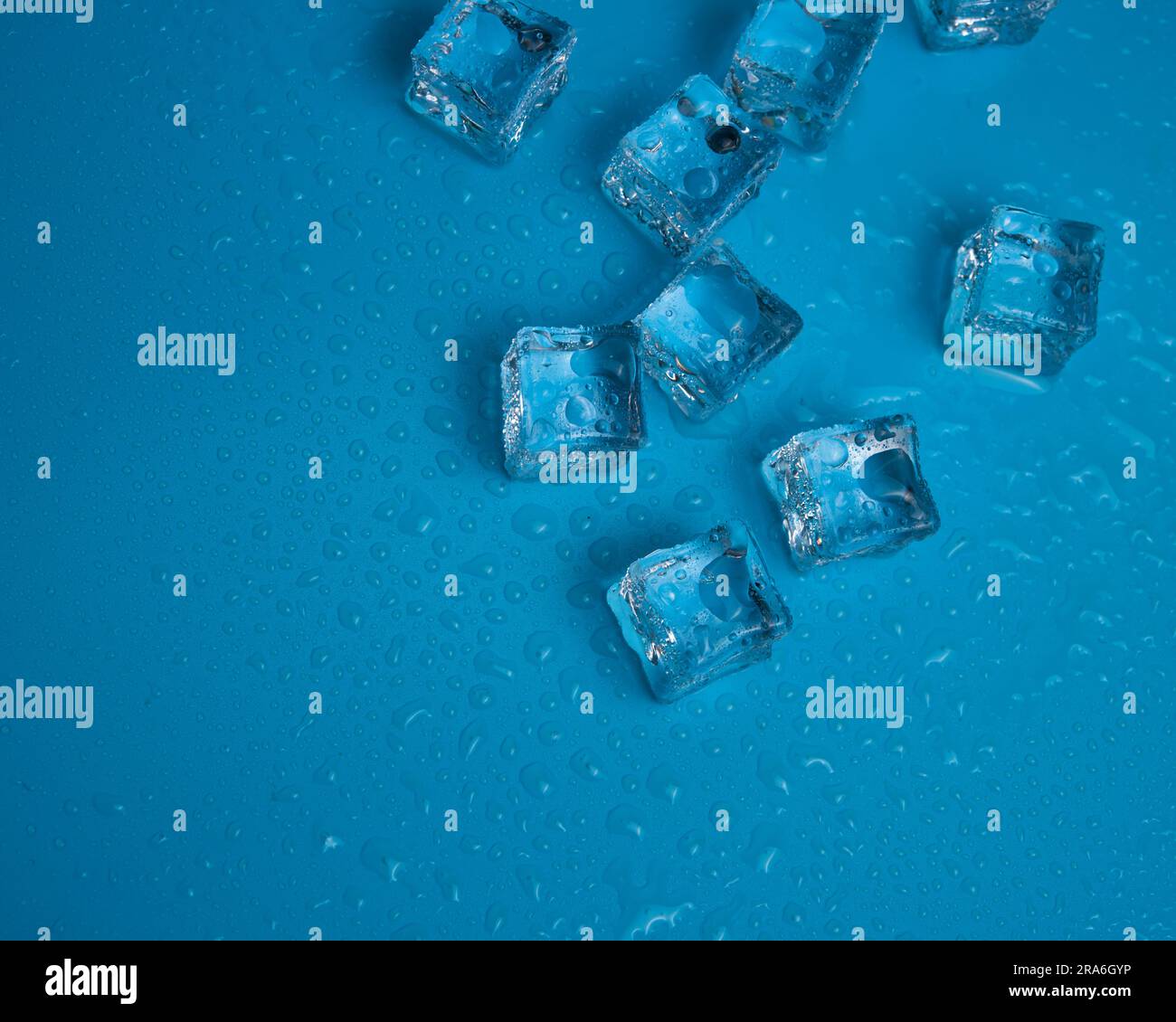 Ice cubes with water drops scattered on a blue background, top view ...