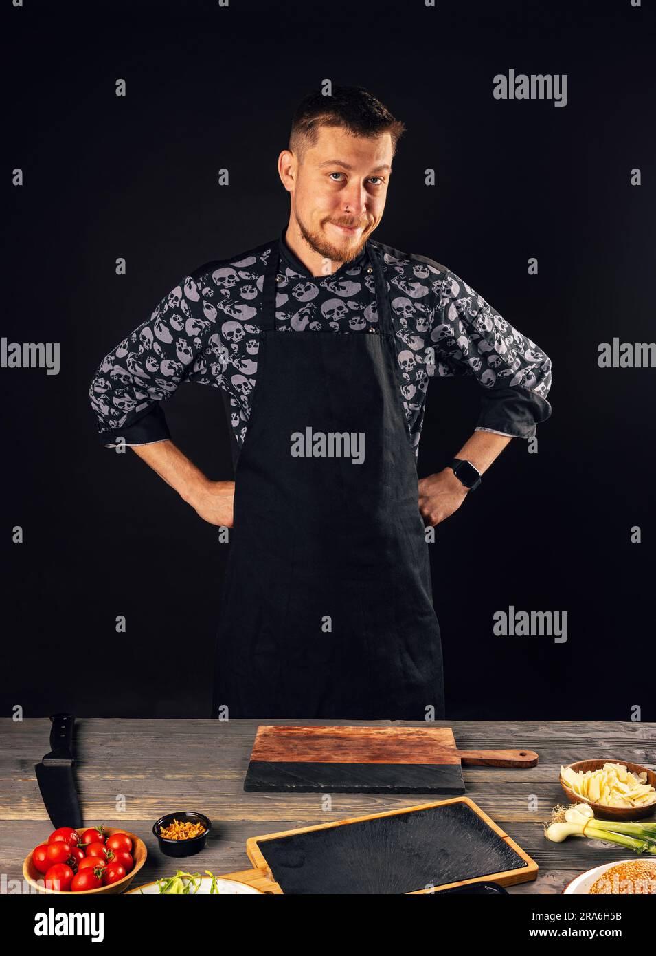 Chef standing next to cutting board with vegetables on it, wearing ...