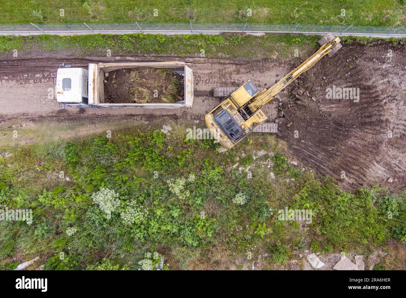 Aerial view of an excavator working removing earth and loading it into a truck dumper on a ...