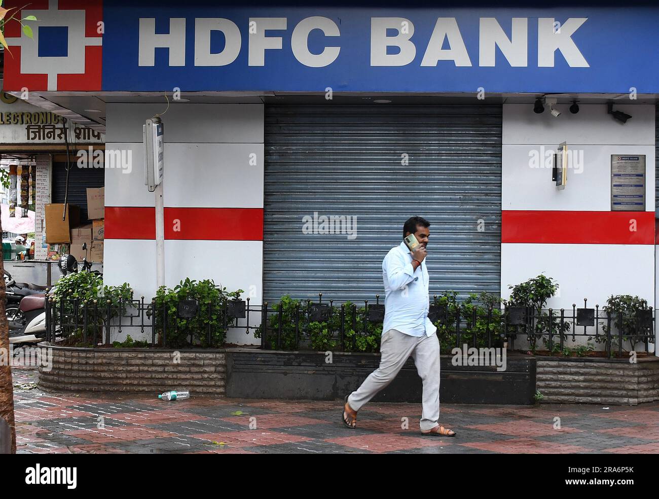 A man talking on his mobile phone walks past HDFC bank branch in Mumbai. Housing Development ...