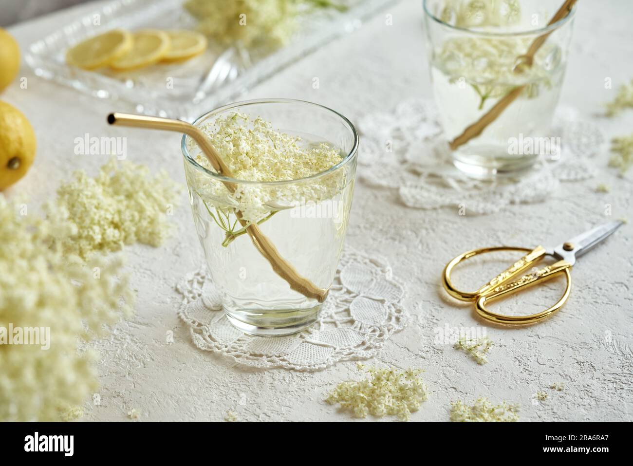 Fresh elderberry flowers in glasses of water with golden metal drinking ...