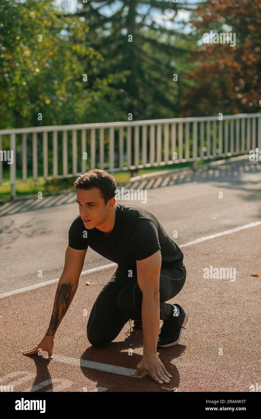 Fit male person doing short sprints on a sports track in the park. He ...