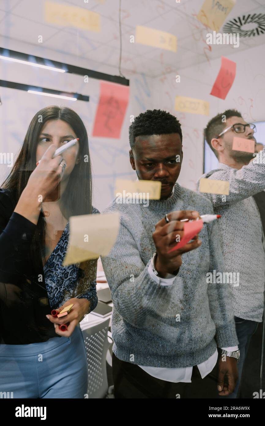 A front view photo of diverse group of young people writing new ideas ...