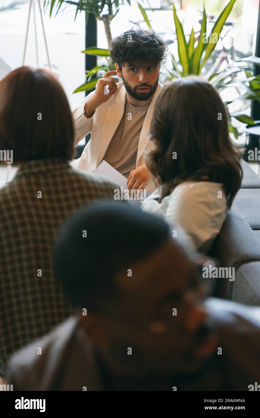 Beautiful 30s male business person listening to his female coworkers ...