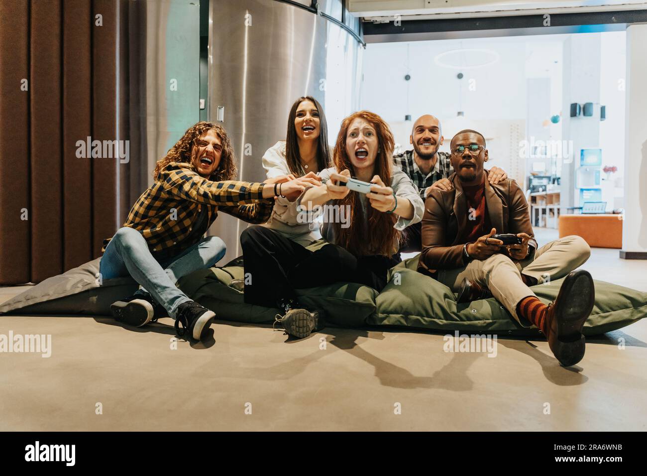 Multi-ethnic, multiracial employees playing electronic games and having ...