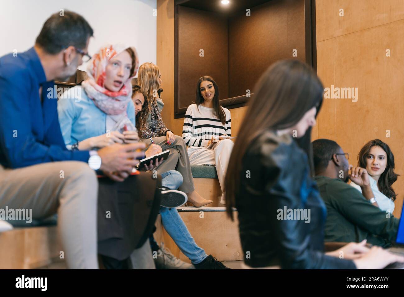 Diverse group of employees working together. Two women discussing ...