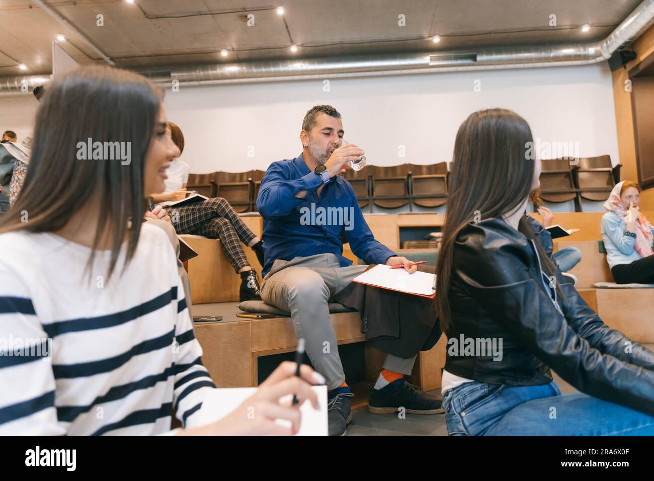 Dehydrated middle-aged business trainer drinking water after giving ...