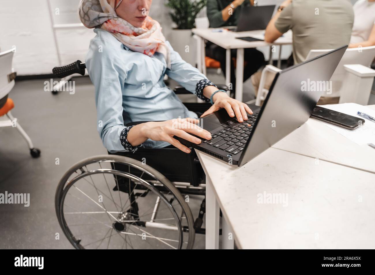 Close up photo of disabled female employee in wheelchair working on lap ...