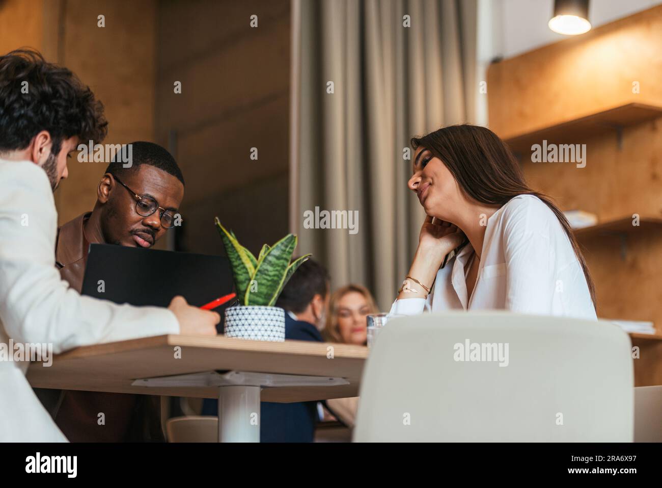 Three young and attractive work friends sitting together and working at ...