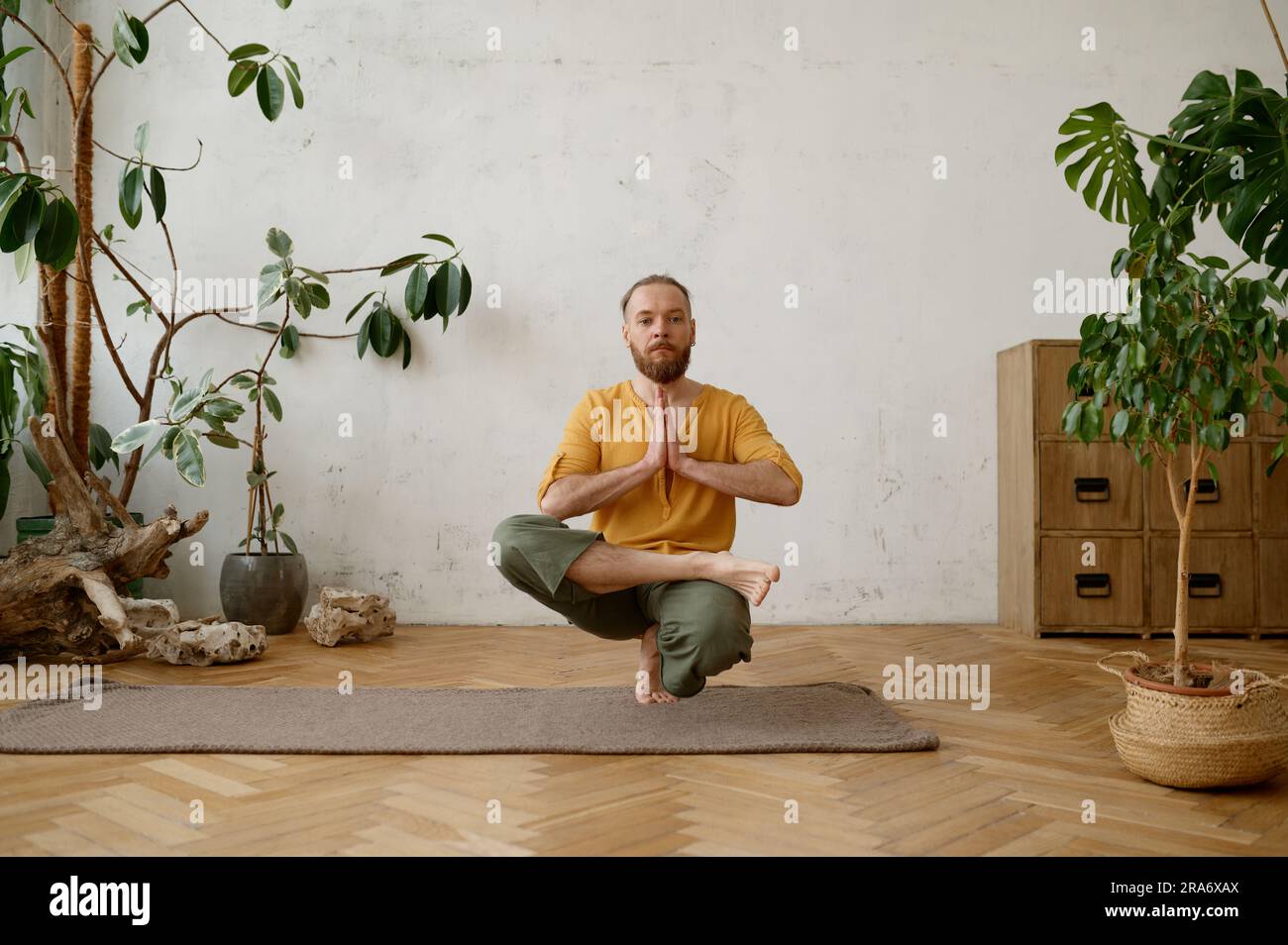 Strong fit man balancing on one leg in squatting position Stock Photo ...