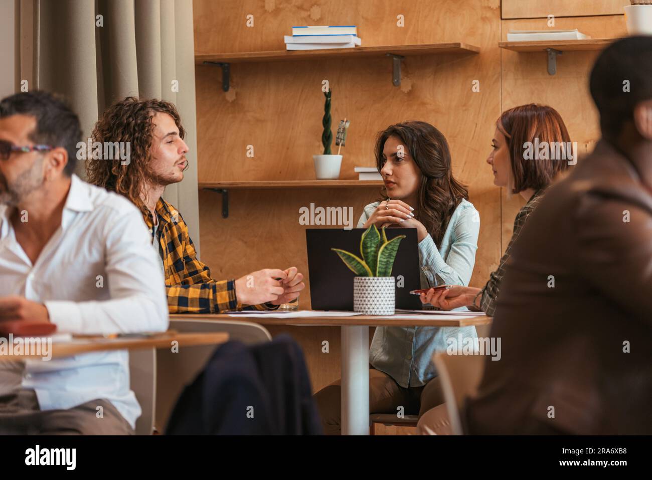 Three young and attractive work friends sitting together and talking at ...