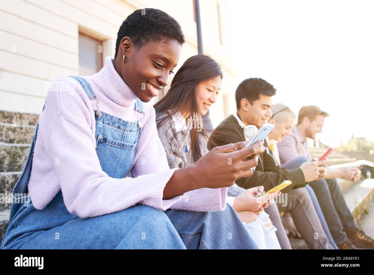 Technology Addicted smiling group of cheerful students using mobiles ...