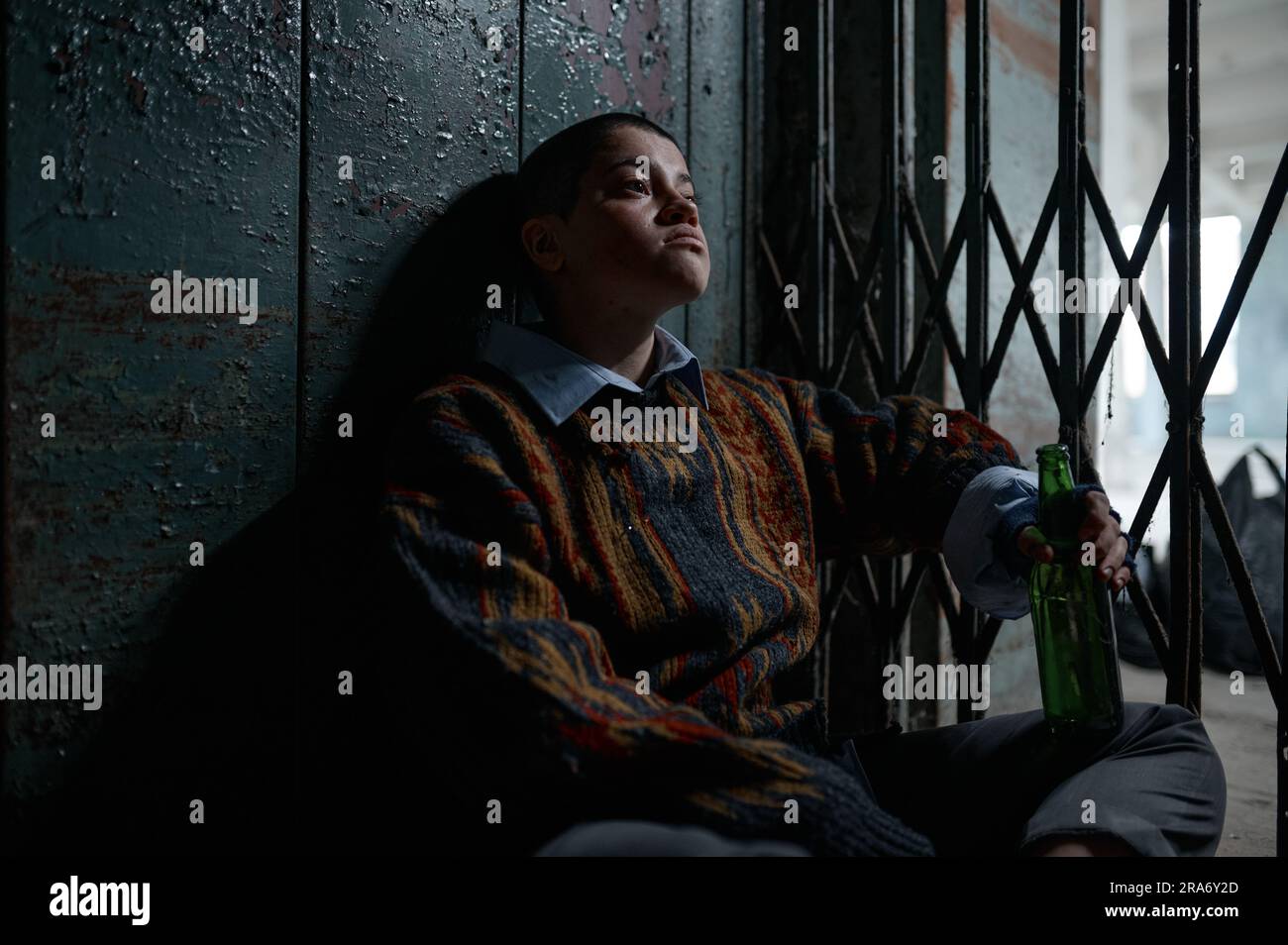 Homeless woman feeling loneliness sitting behind bars drinking beer ...