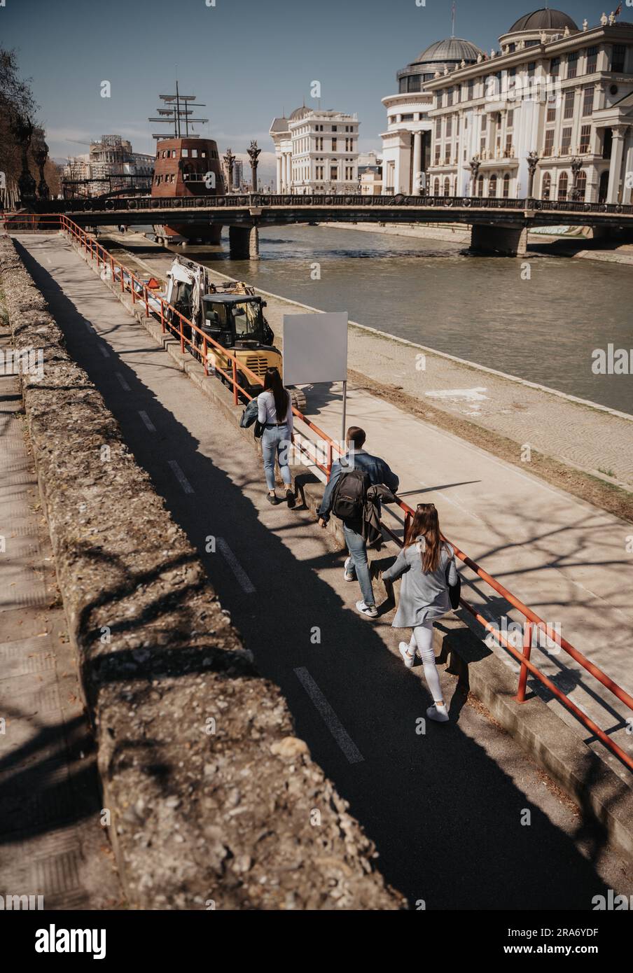 Three people, two girls and one boy walking and going up to the city ...