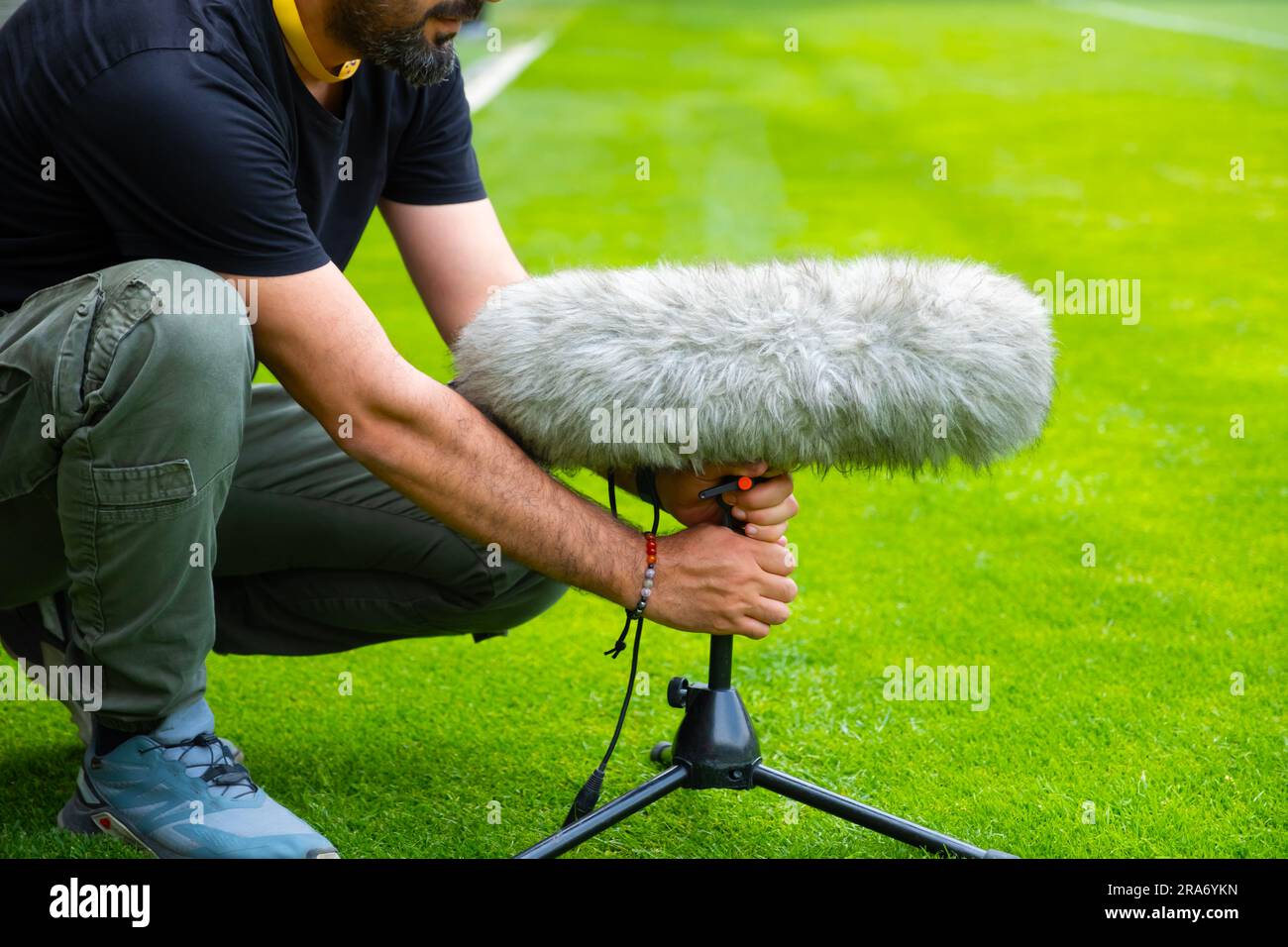 A sound technician is placing a shotgun microphone at the edge of the ...