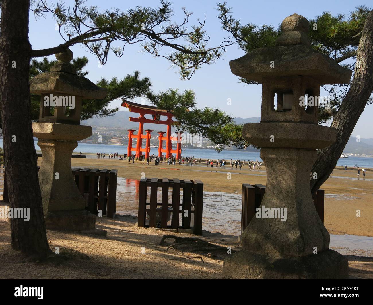 Viewed between two stone lanterns, the red Torii Gate on the beach at ...