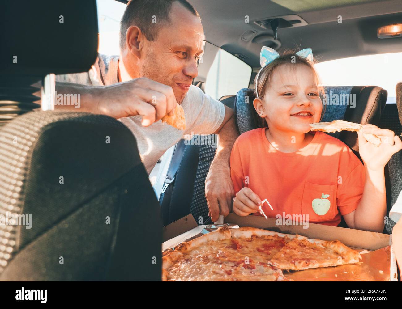 Smiling girl in child car seat while family car trip brake stop eating ...