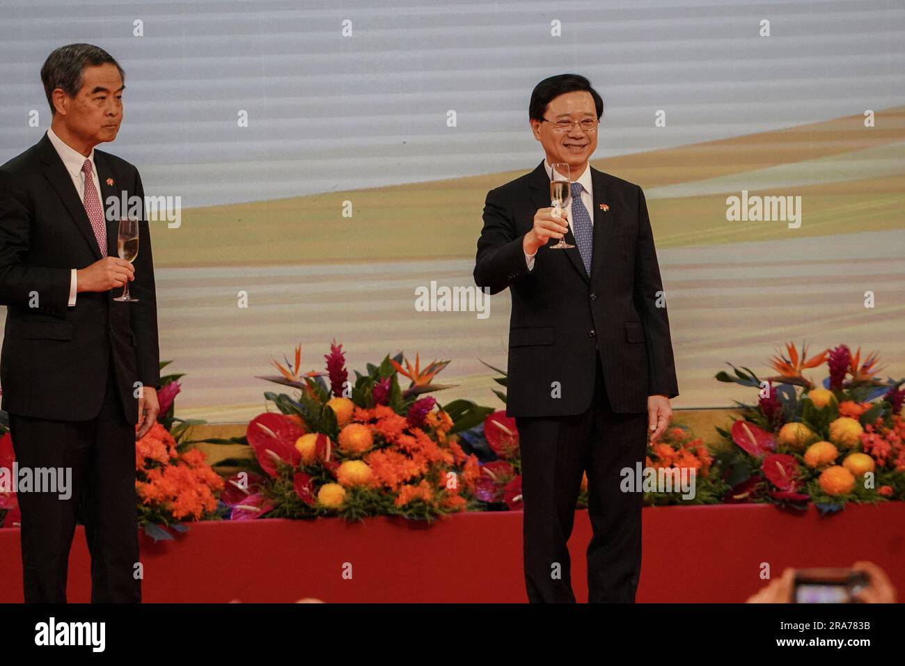 John Lee Ka-chiu (right), holds a glass of wine during the handover ...