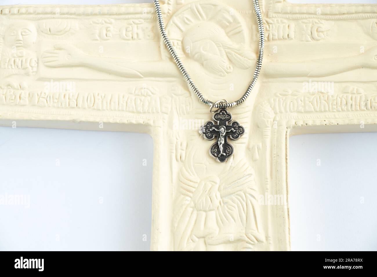 christian plaster cross and silver cross on chains on a white ...