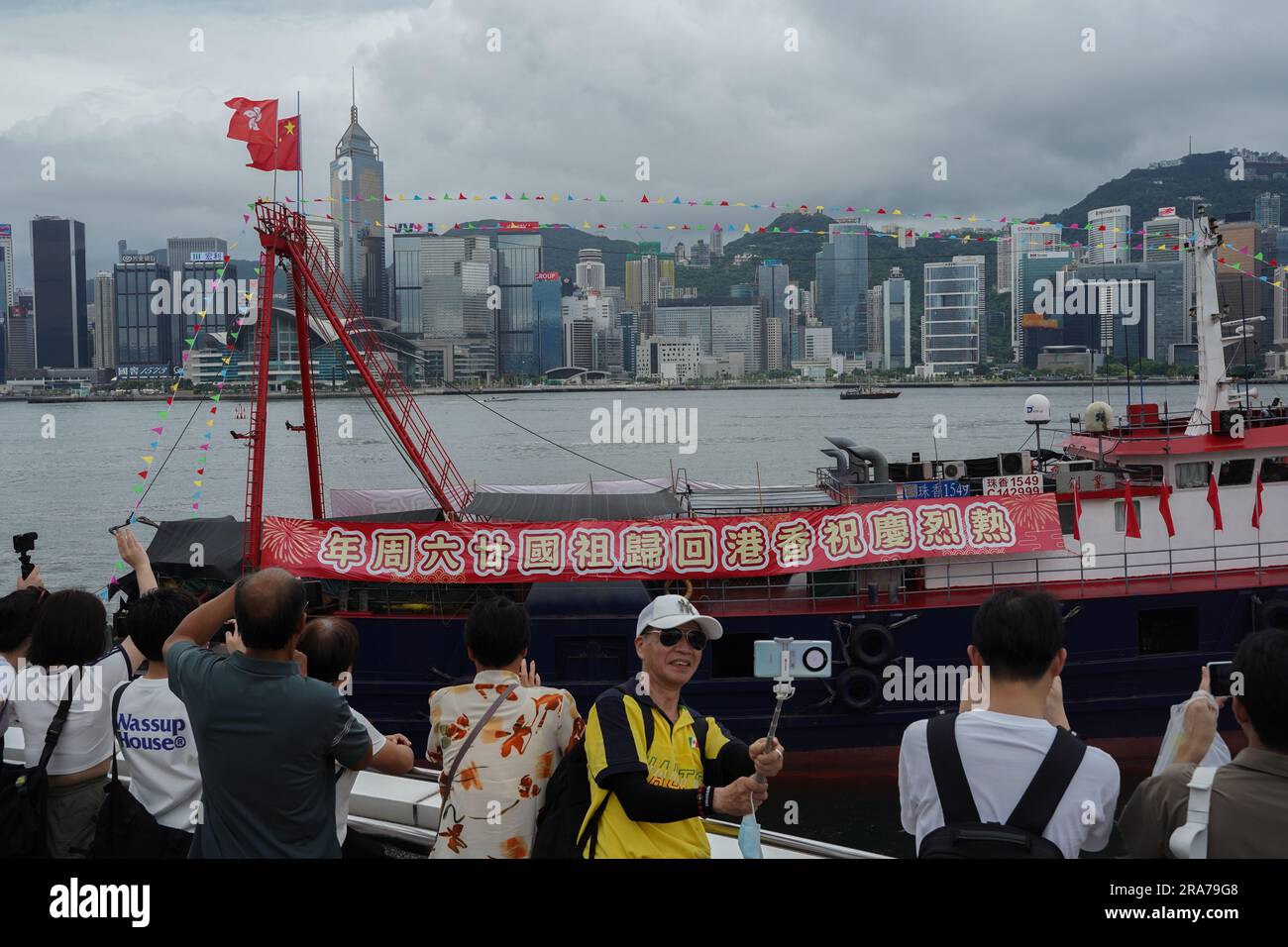 People take photos with a boat that hangs a slogan for celebrating ...