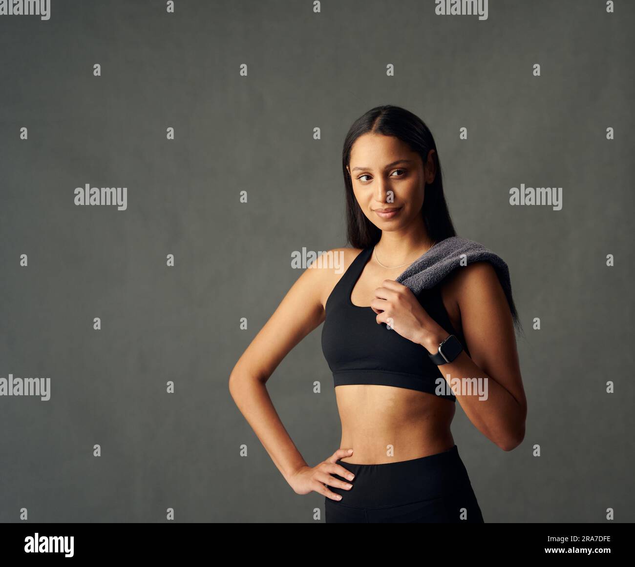 Young biracial woman wearing sports bra and fitness tracker holding ...