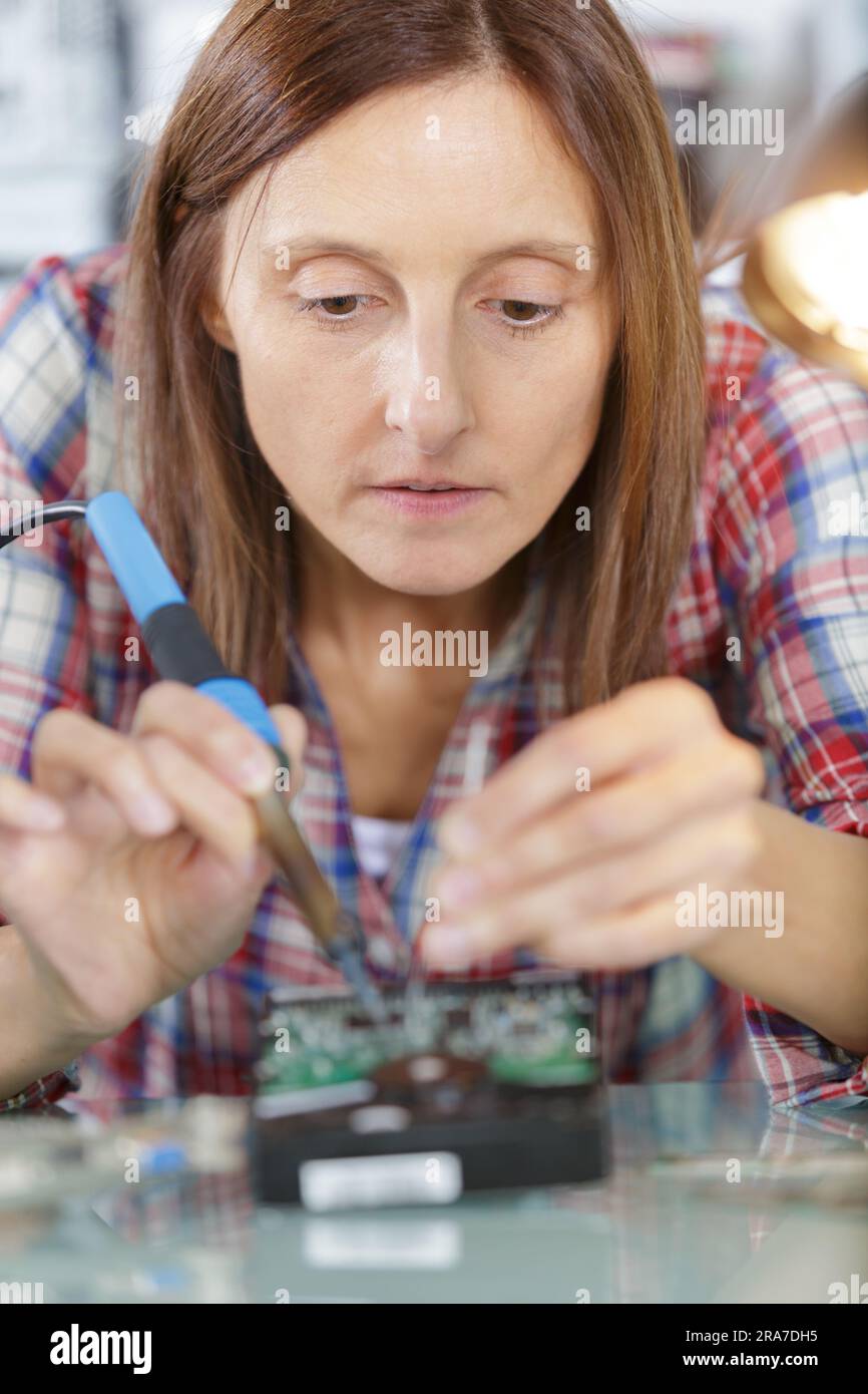 woman soldering elements of circuit board Stock Photo - Alamy