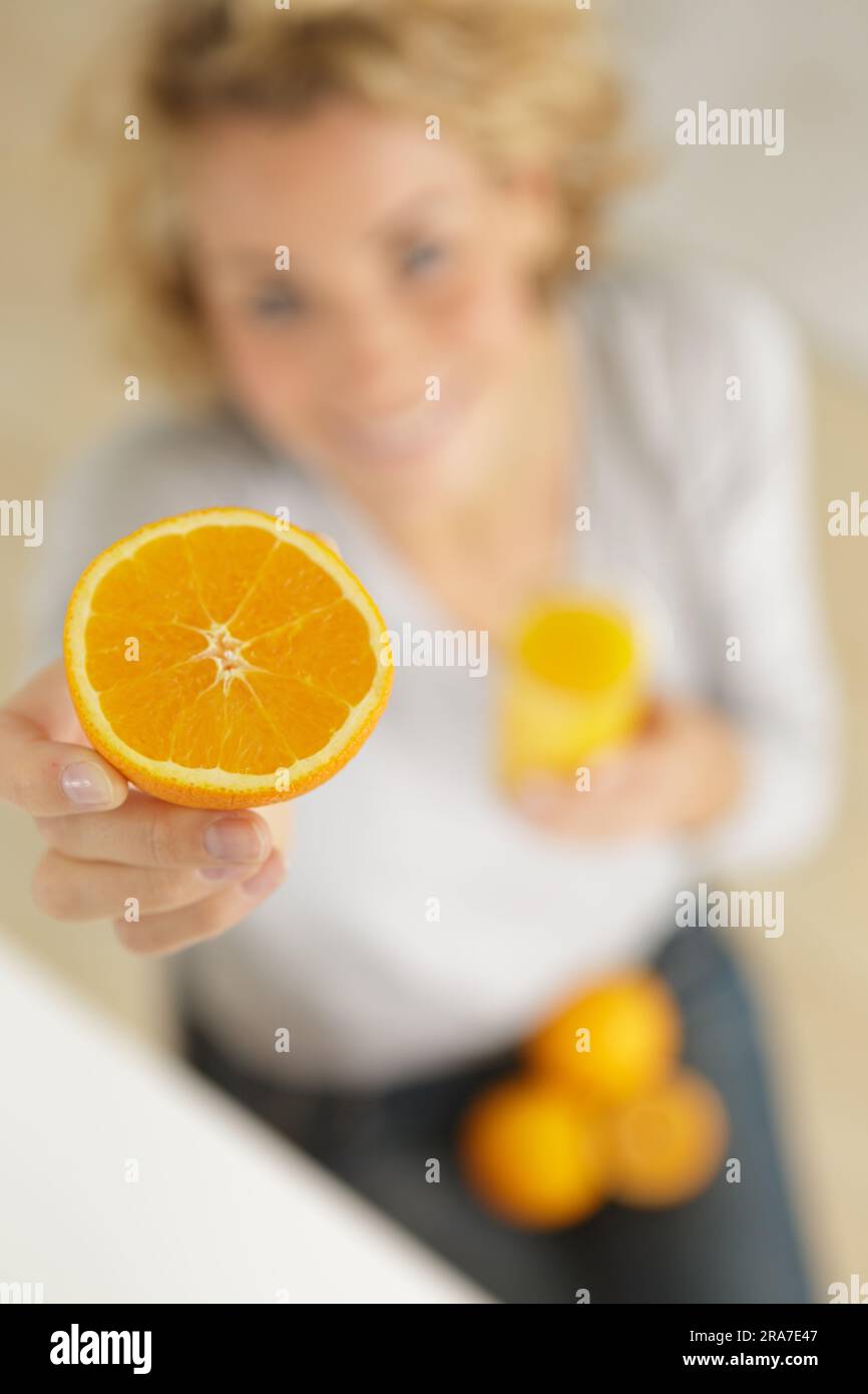 half an orange held by woman blurred in background Stock Photo - Alamy