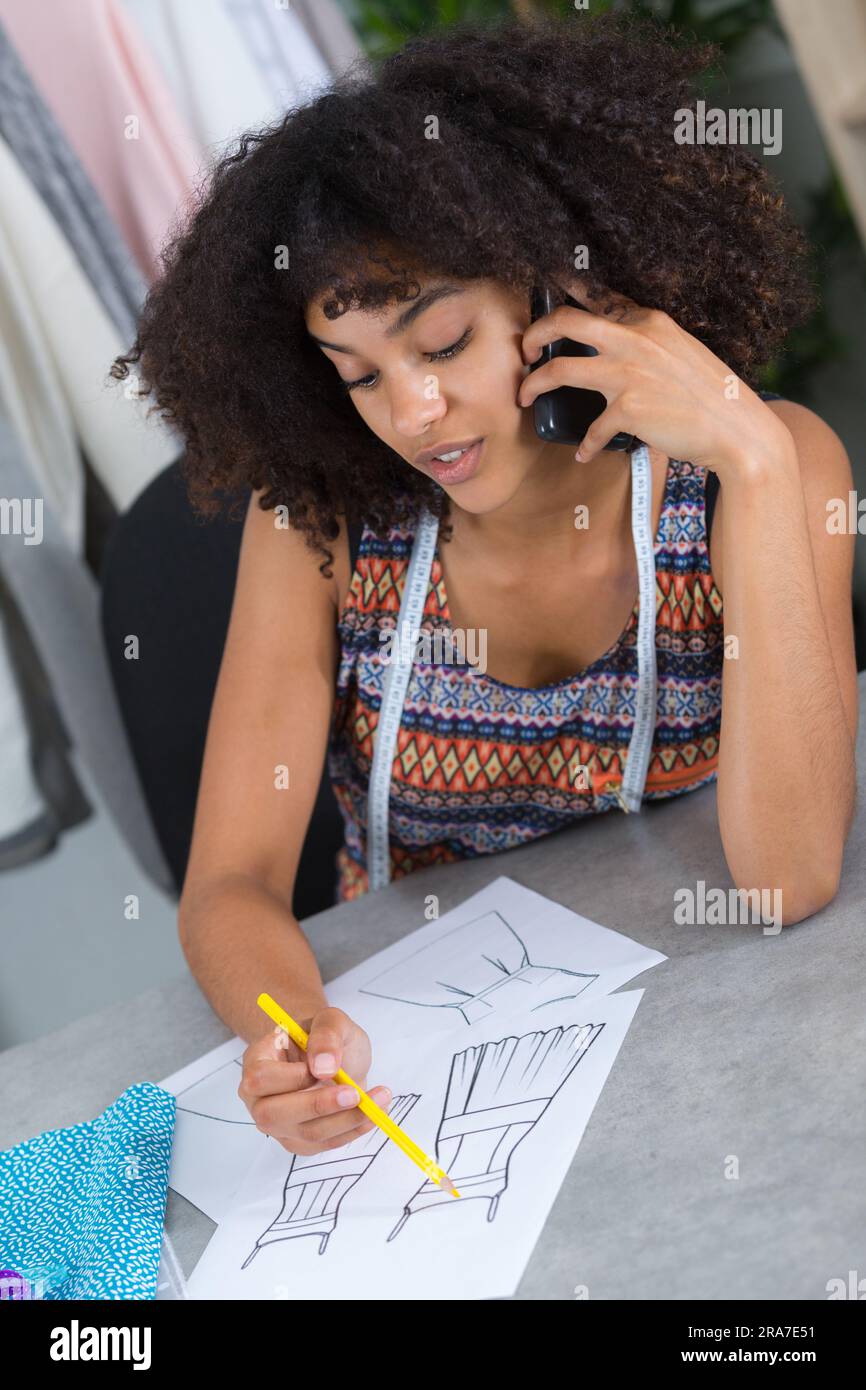 dressmaker sketching while talking on smartphone Stock Photo - Alamy