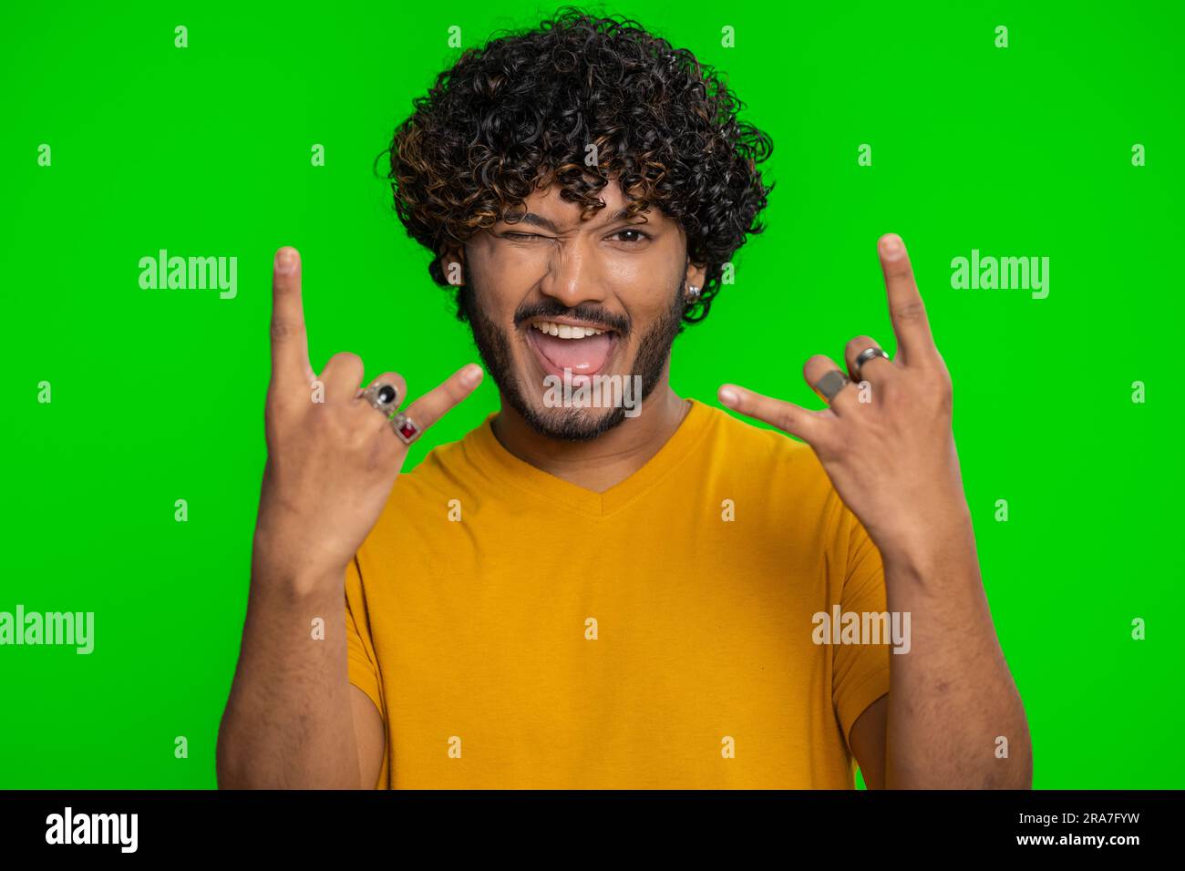 Overjoyed young indian man showing rock n roll gesture by hands, cool ...