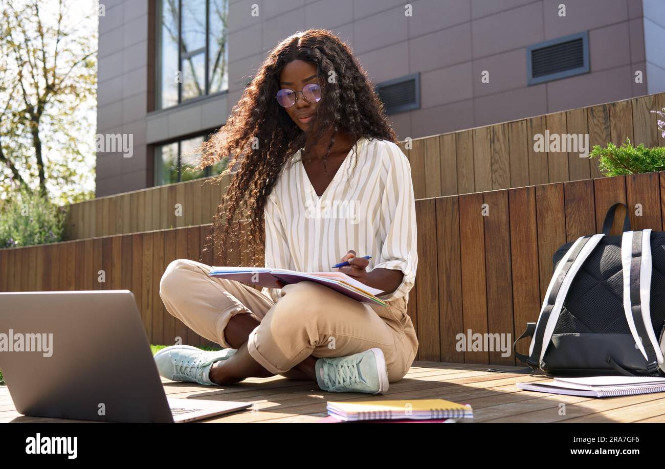 African female student writing notes elearning using laptop studying ...